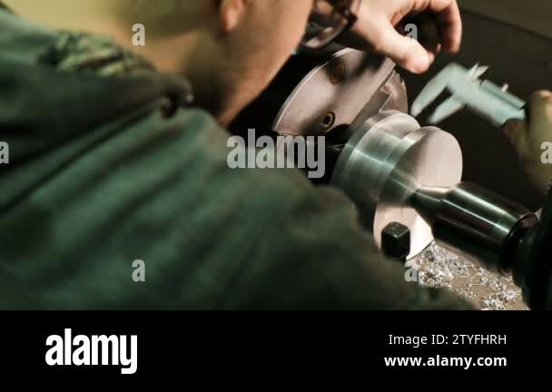 Turner measures the dimensions of the metal workpiece with a caliper ...