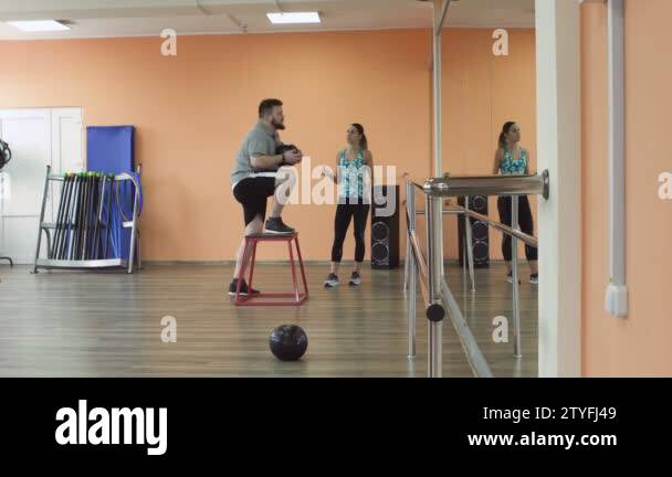 Thick obese guy together with personal slim coach do physical jerks in ...