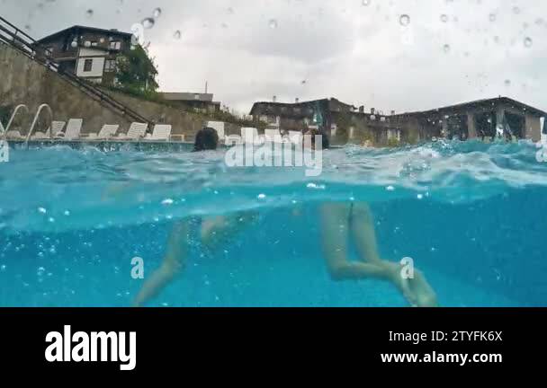 Two girls splashing in pool with legs at rainy weather, gopro dome half ...