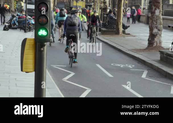 Cyclists ride in a busy cycle lane in London with cycle traffic lights ...
