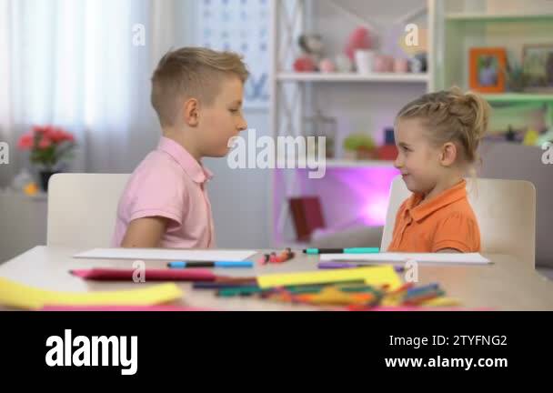 Male and female schoolkids playing together slapping face each other ...