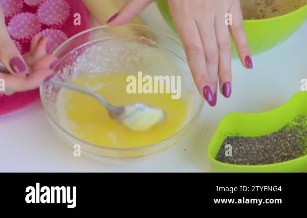 A woman drops cocoa powder into melted butter and mixes. For making ...