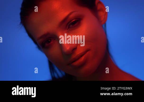Close-up shoot of fashion model in red and blue neon lights closing ...