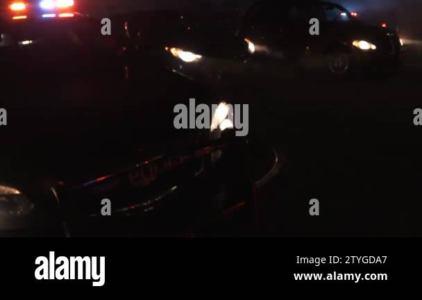 Police cars with flashing lights parked along roadside establish a ...