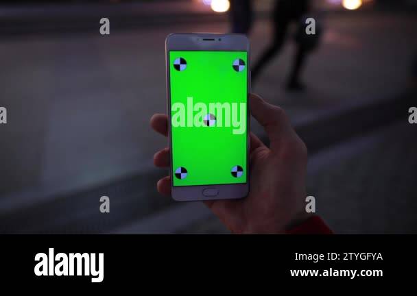 1st person view, using blank screen of smartphone sitting in night city ...
