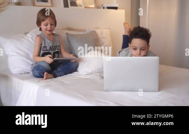 Boys in parents bed at morning with laptop and tablet. Brothers play ...