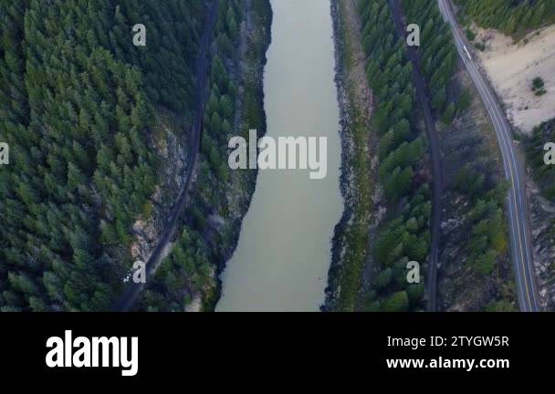 Fly over the river with railroad on the both sides and small road with ...