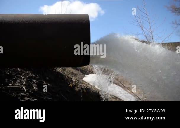 A black storm drain pipe with storm water runoff flowing out of it into ...