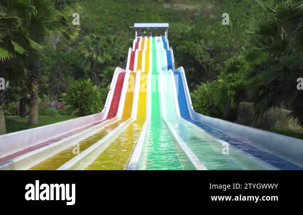 People sliding on colorful water slide at aquapark at summer vacation ...
