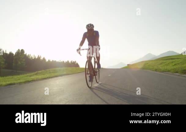 LOW ANGLE LENS FLARE Pro biker man with sunglasses pushes himself to ...