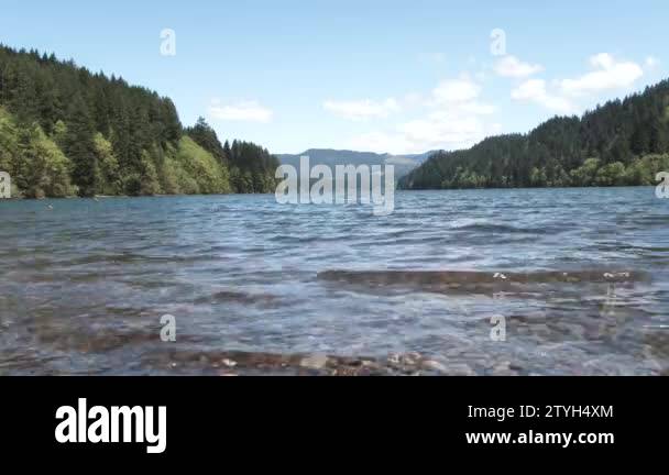 Water approaches camera from low angle on small stone shore of fresh ...