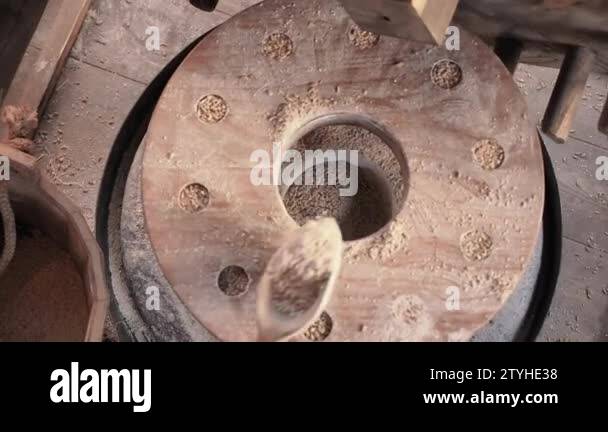 The ancient quern stone hand mill with grain. The man grinds the grain ...