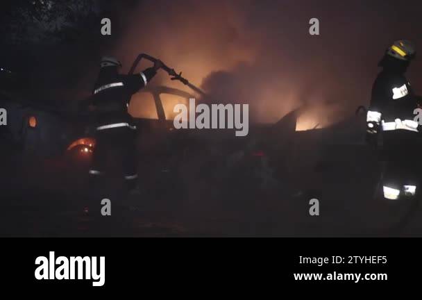 Fire of a car on city street man trying to put out a fire with ...