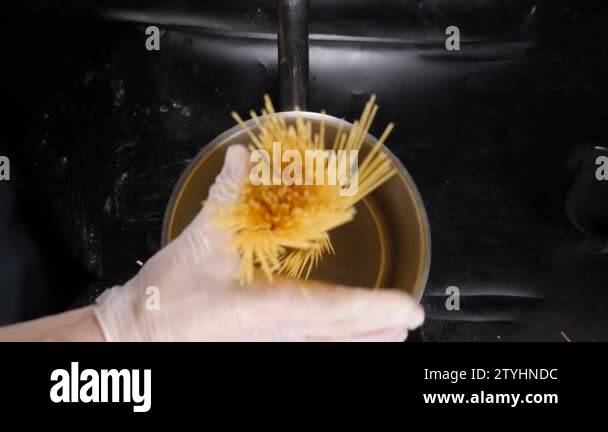 Top view on throwing spaghetti pasta into boiling water. Overhead shot ...