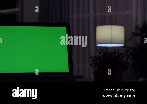 Laptop with green screen. Dark office. Perfect to put your own image or ...