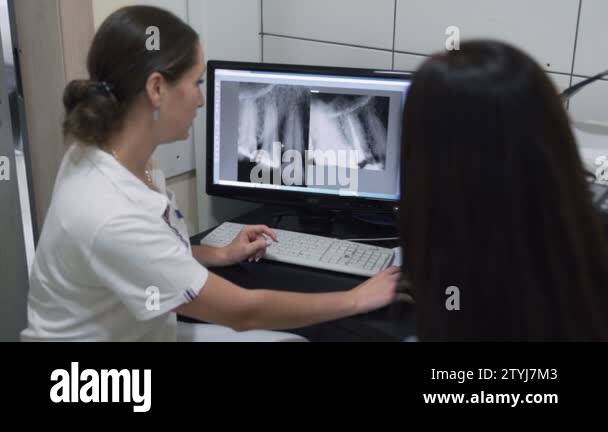 Dentist shows to patient an x-ray picture of the jaw on screen, slow ...