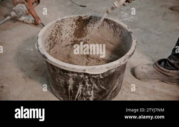 Concrete industry - worker adding water in the bucket full of dry ...