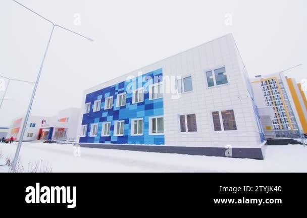 school building with bright walls and playground at snowfall Stock ...