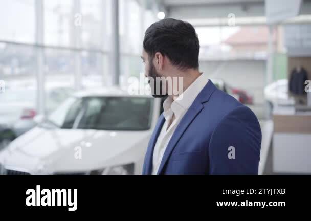 Portrait of successful Middle Eastern man posing in car dealership ...