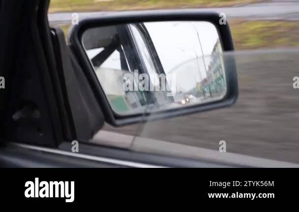 View through the dirty mirror of a retro car, a house road and a car ...