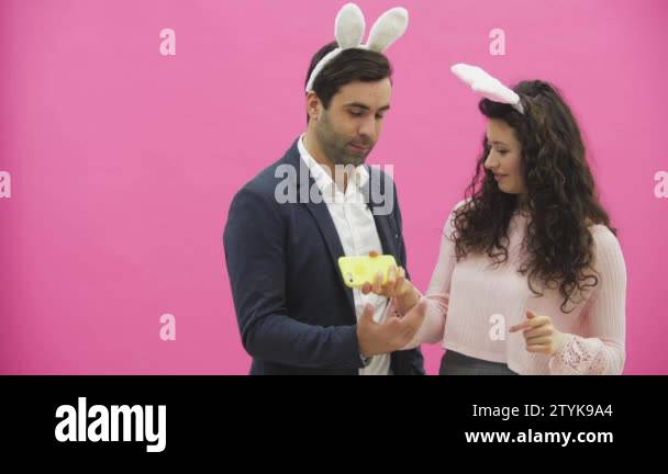 Young lovers couple on the pink background. With hackneyed ears on the ...