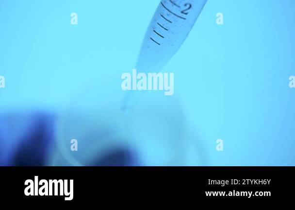 In the laboratory, a scientist with a pipette analyzes a colored liquid ...