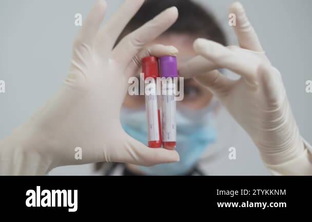 Woman doctor holding vacutainers with blood, shaking blood collection ...