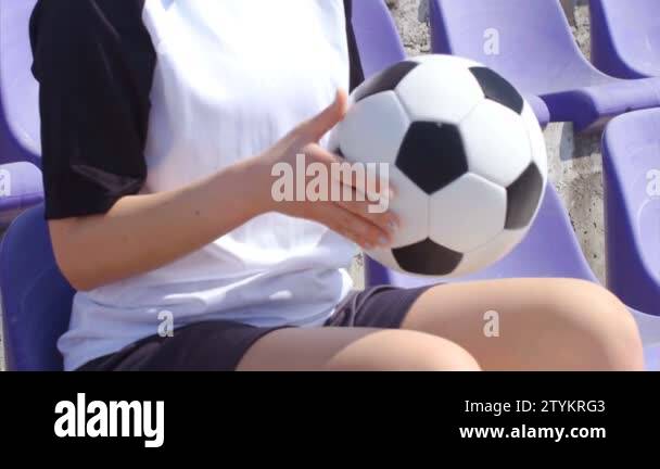 Young woman footballer seating with a football soccer ball on the ...