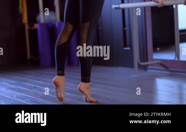 barefoot dancer with long ponytail in black bends body backward putting ...