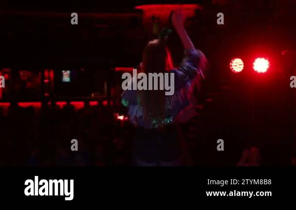 Girl who sings and dances on stage, Back view of singer. Light and ...