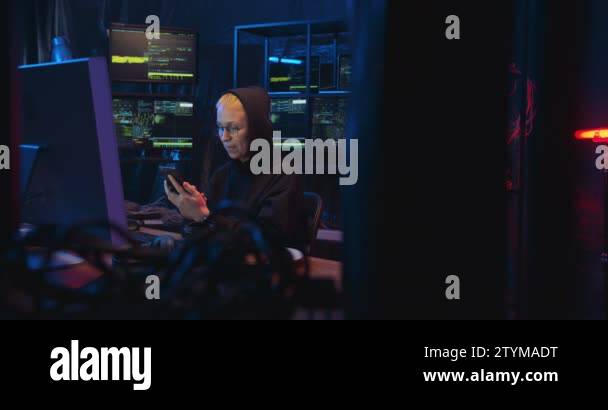 Female Caucasian hacker sitting in front of big screen and tapping or ...