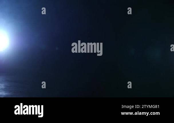 Bright spotlight shines in dark. Camera moves from right to left ...