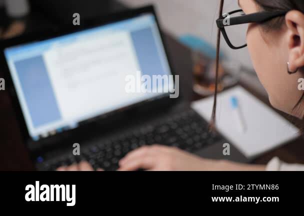 Blurred female hands girl with glasses at night typing on laptop ...