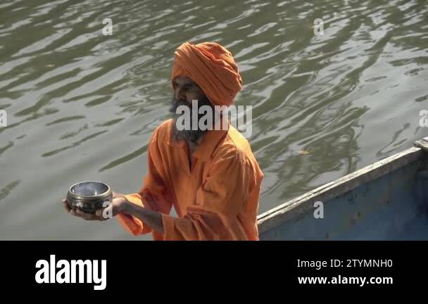 Indian monk floats in a boat with a holy cup, to an old temple, and ...