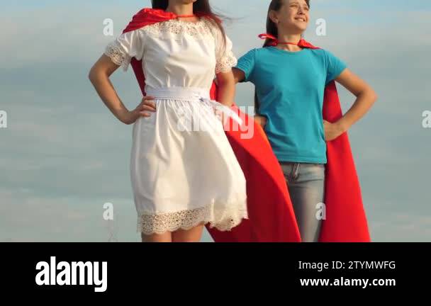 two girls in red cloaks of superheroes stand against a blue sky, the ...