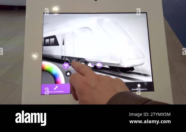 Exhibition visitor choosing the color of future trains on a tablet with ...