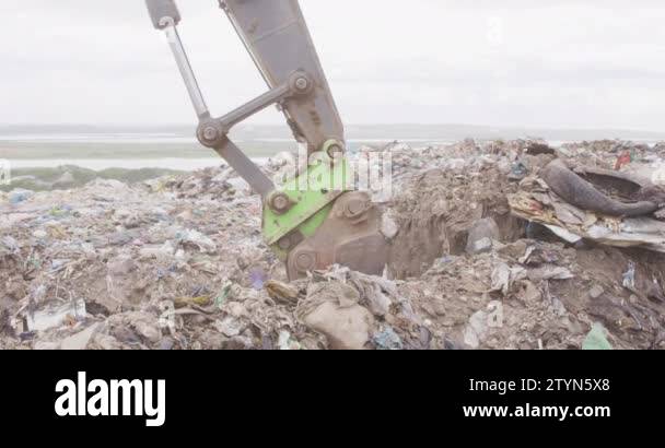 Side view close up of digger working and clearing rubbish piled on a ...