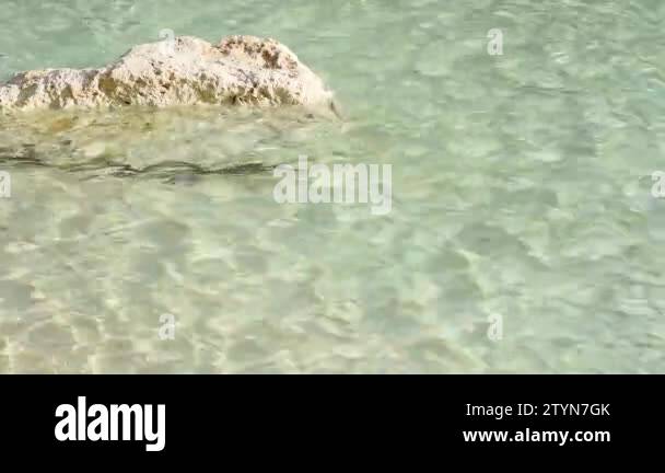 Big rock with water flowing around it. small water ripples under the ...