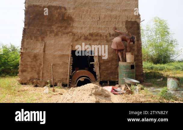 man covering with mud over the entire surface of a tobacco barn for a ...