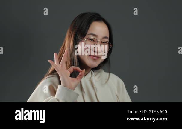 Young asian woman making OK sign over grey background. Winner. Success ...