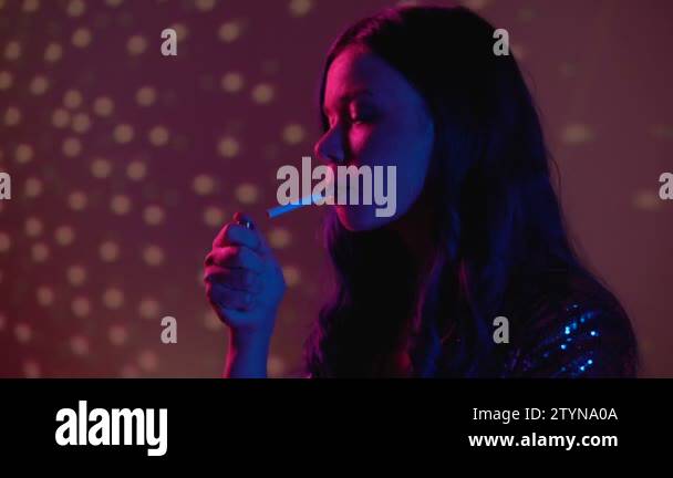 Serious young woman smoking cigarette at nightclub party, unhealthy ...