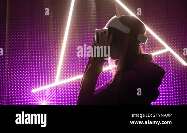 Young girl professional gamer wearing virtual reality glasses. Immersed in a parallel reality ...