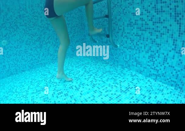 Fashion model girl feet go out of swimming pool on metal ladder stairs ...