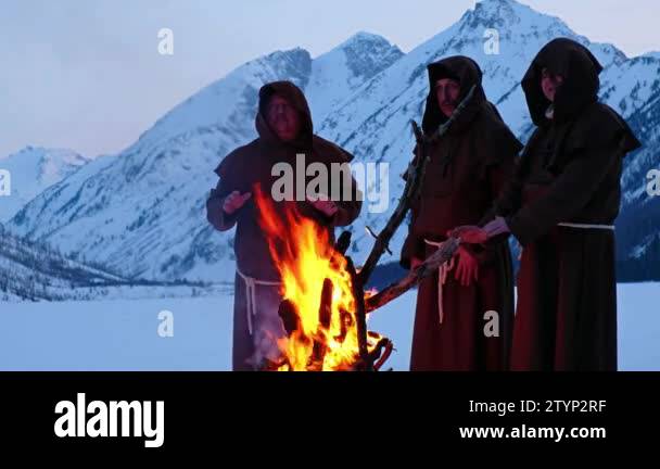 Group of monks in brown cloaks of the order of St. Francis are warming ...