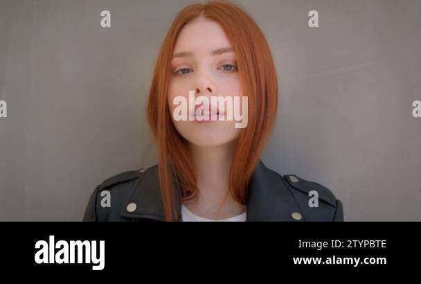 Young female ginger rocker in leather jacket watching peacefully into ...