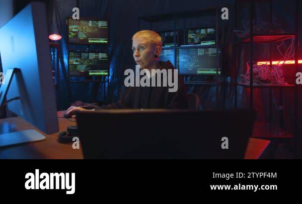 Female Caucasian hacker working on computer in front of big screen and ...