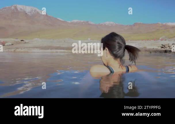 Woman taking a bath at El Tatio Geysers hot springs at Atacama desert, amazing thermal spring ...