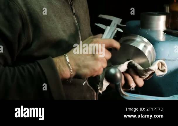 Turner measures the dimensions of the metal workpiece with a caliper ...