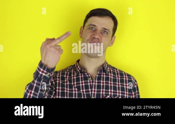 A funny, handsome guy shows indecent hand gestures. Portrait of a young ...