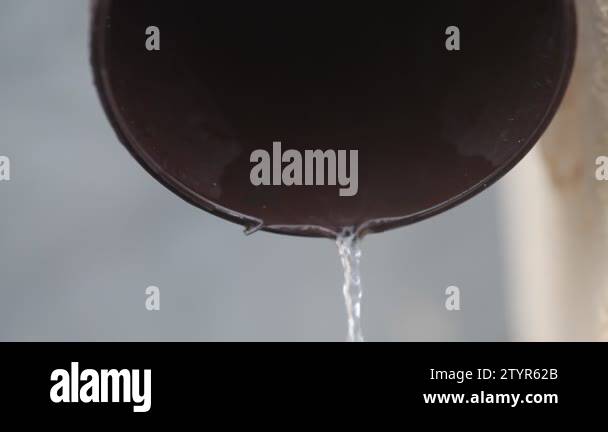 Water flows from a pipe. Rainwater flowing from drain pipe closeup ...